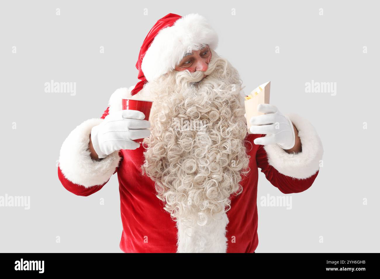 Santa Claus with cup of cola and tasty french fries on white background ...