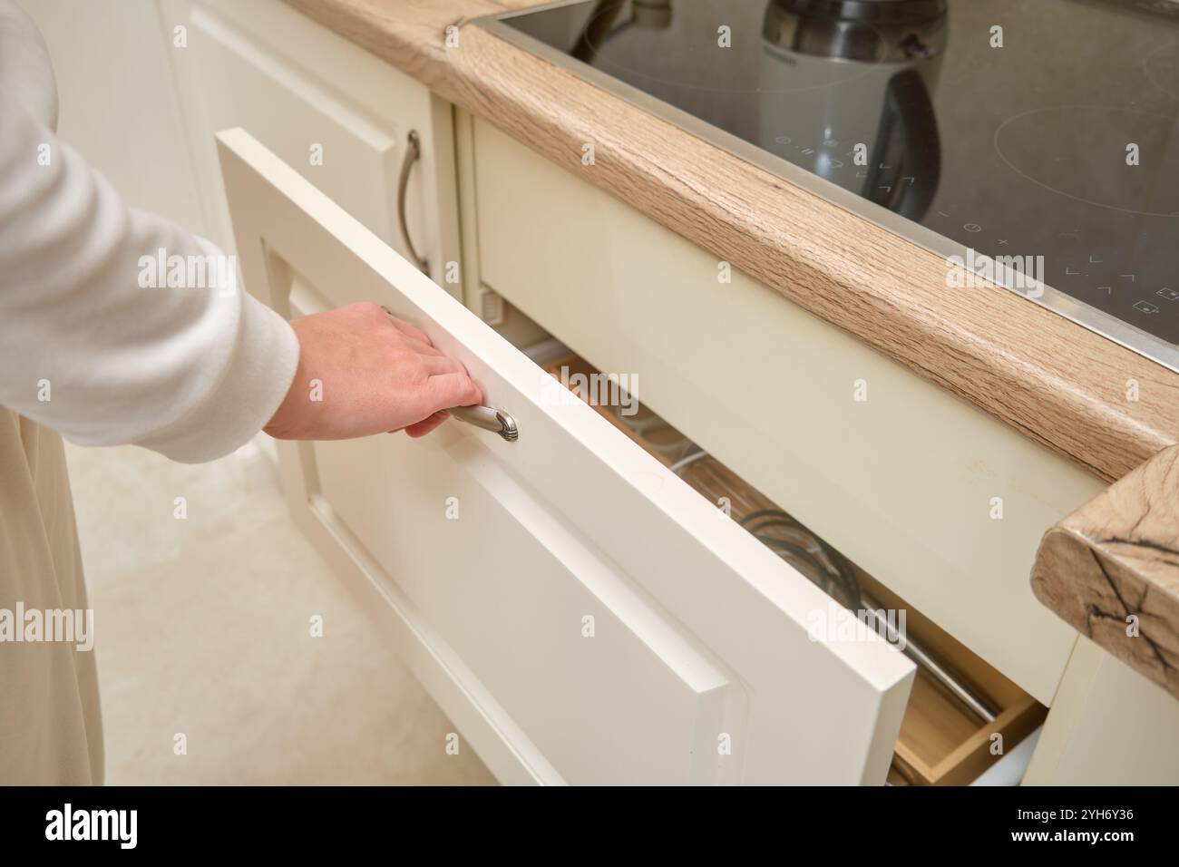 Hand opening white kitchen drawer below wooden countertop with built-in ...