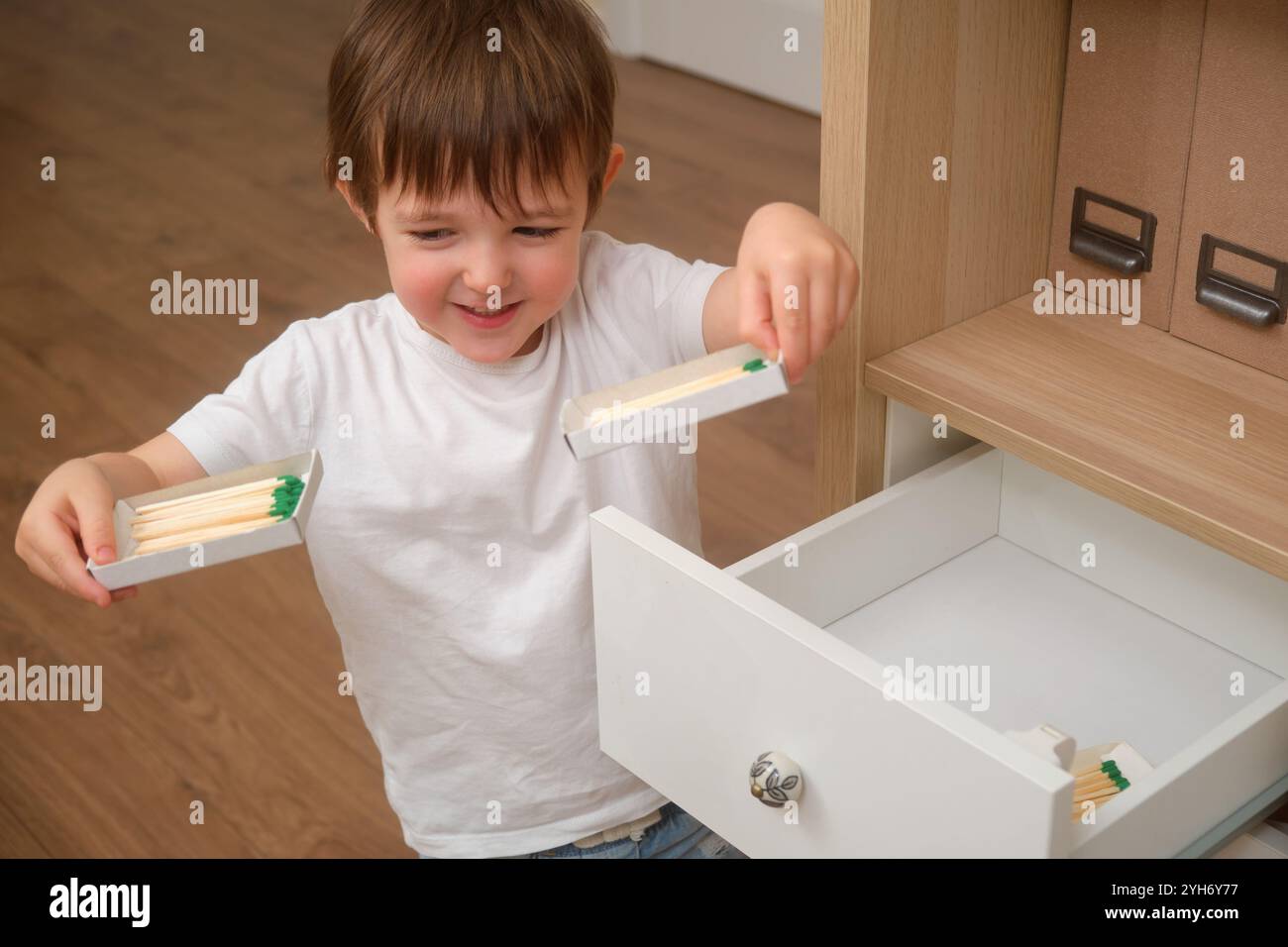 A child boy is holding a lit matchstick, which is highly flammable and ...