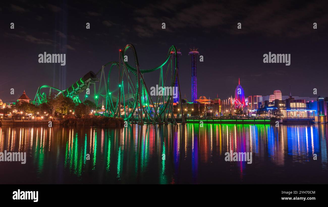 A vibrant nighttime scene of roller coasters at a Theme park, with colorful lights reflecting on ...