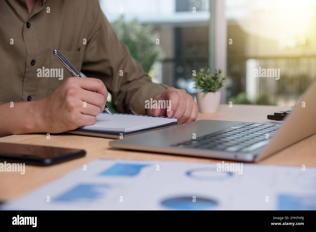 Businessperson writing notes while planning in an office setting ...