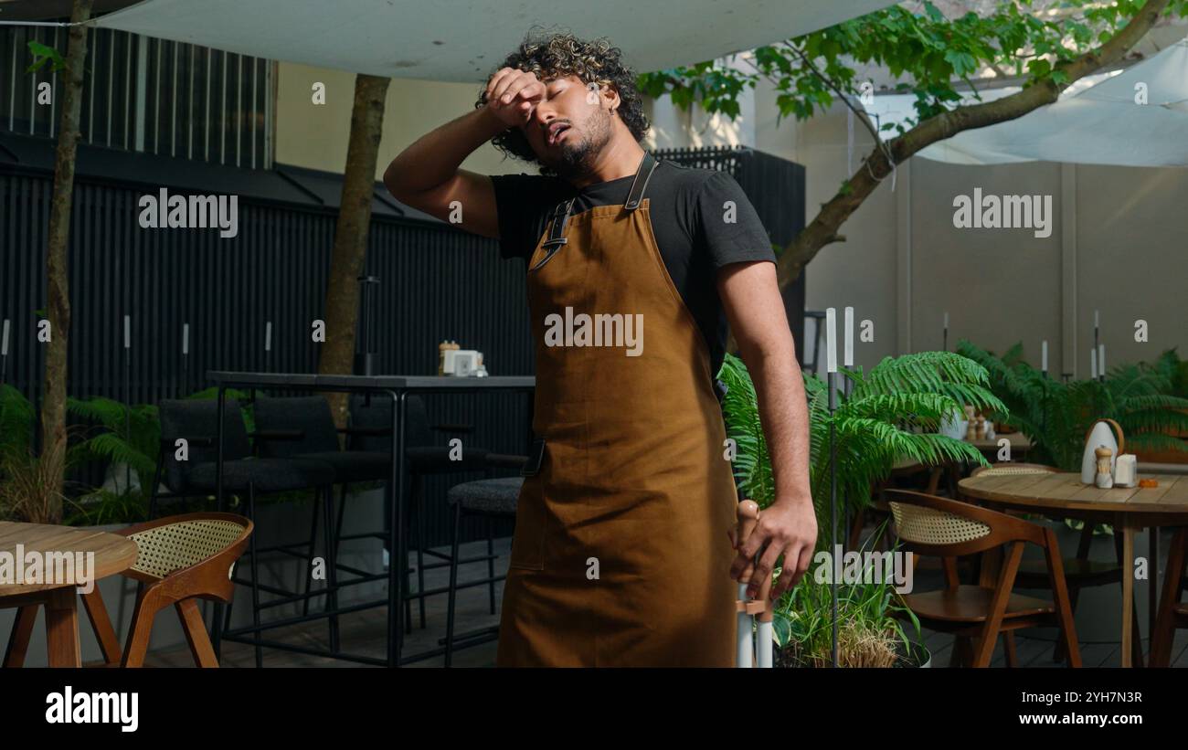 Tired exhausted Indian Arabian ethnic male man guy in apron waiter ...