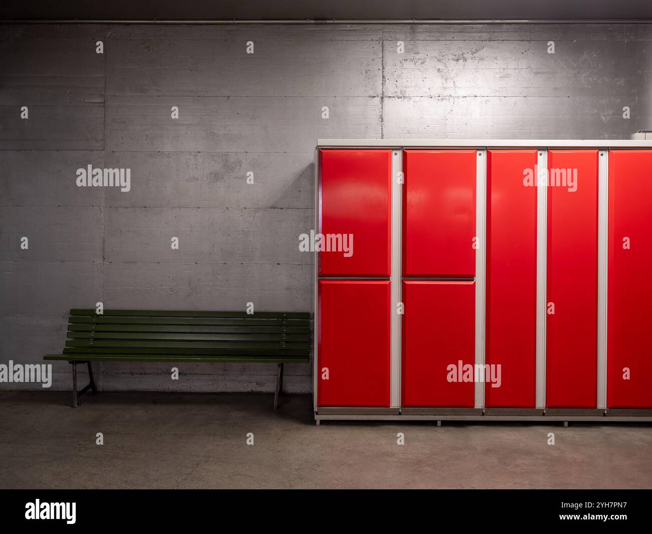 Red metal lockers, ski, luggage storage near green bench on concrete ...