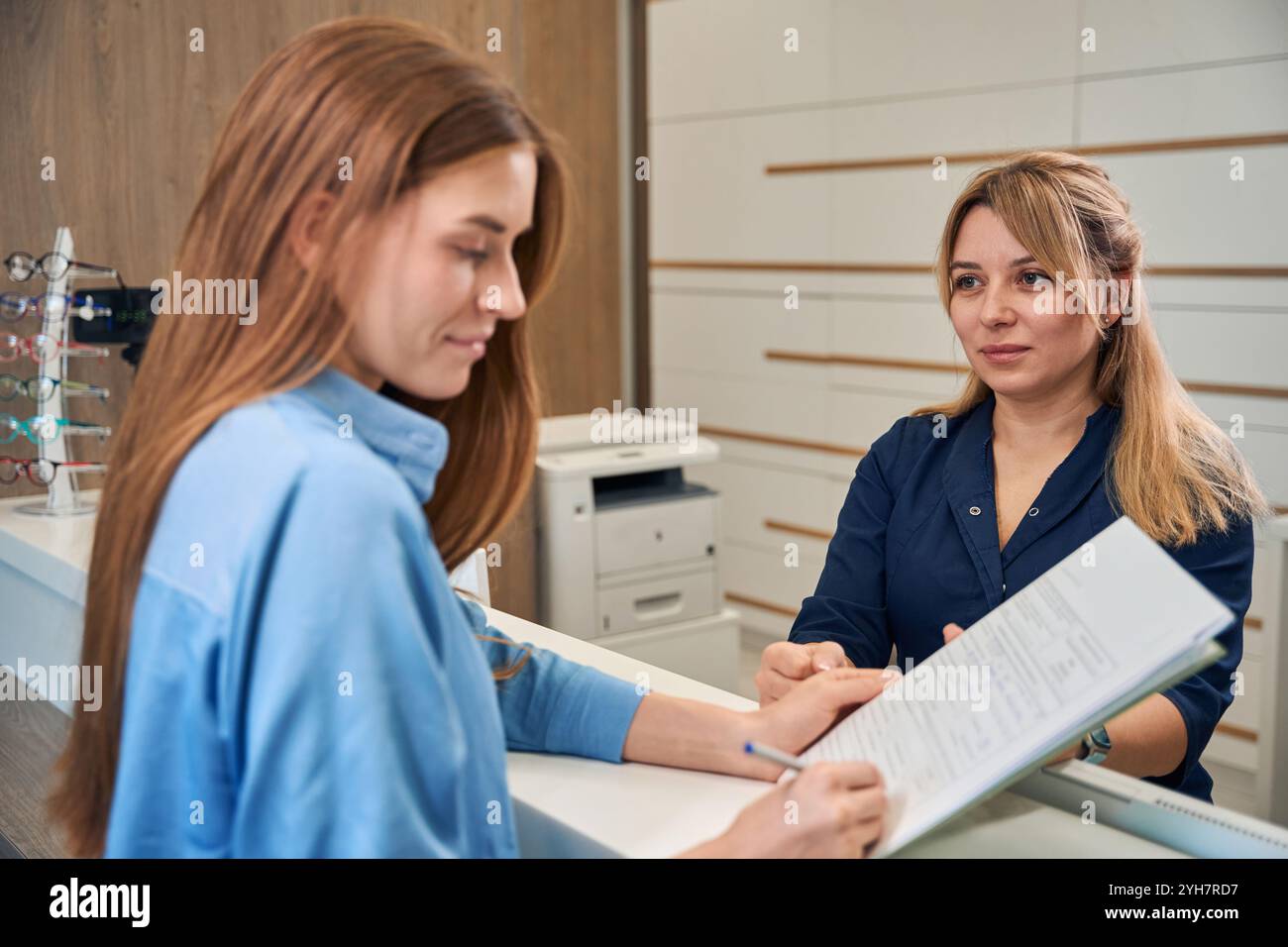 Female adult patient reviewing documents with receptionist Stock Photo ...