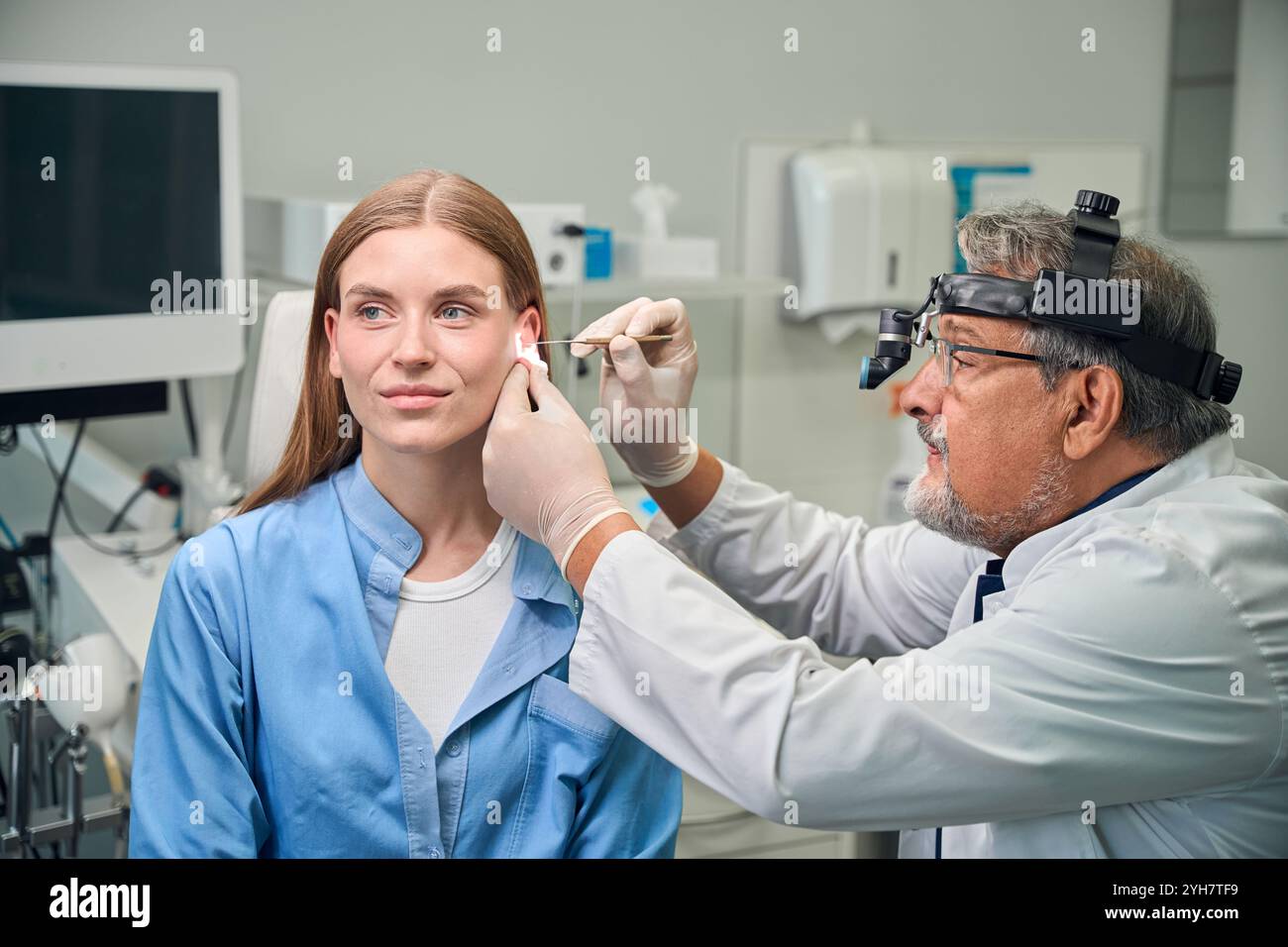 Adult doctor using medical tool to inspect ear Stock Photo - Alamy