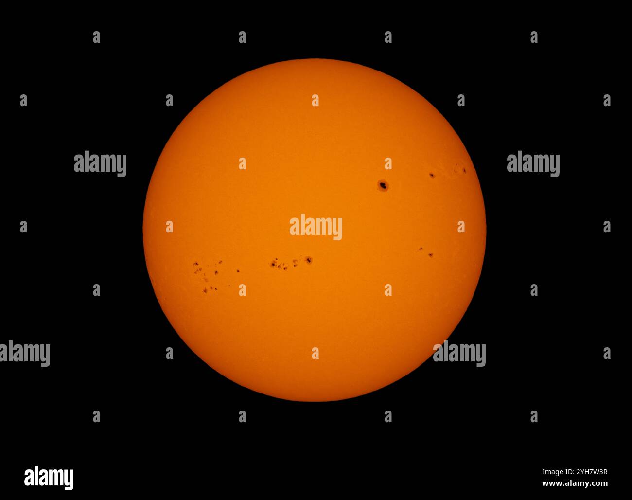 The orange coloured afternoon sun glowing with many large sunspots ...