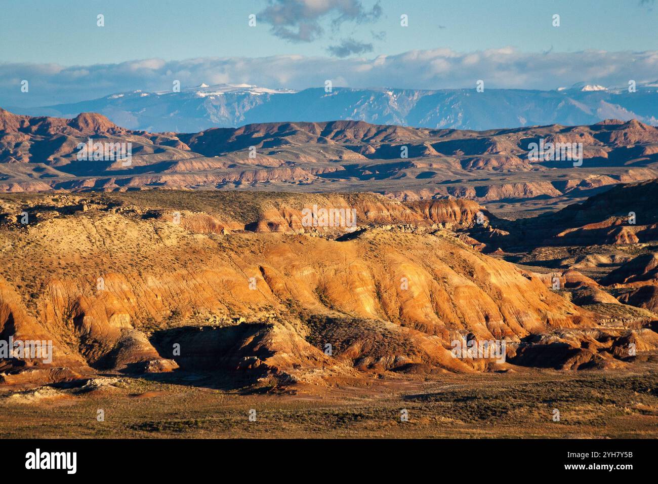 The Absaroka Mountains rising in the distance beyond badlands hills ...