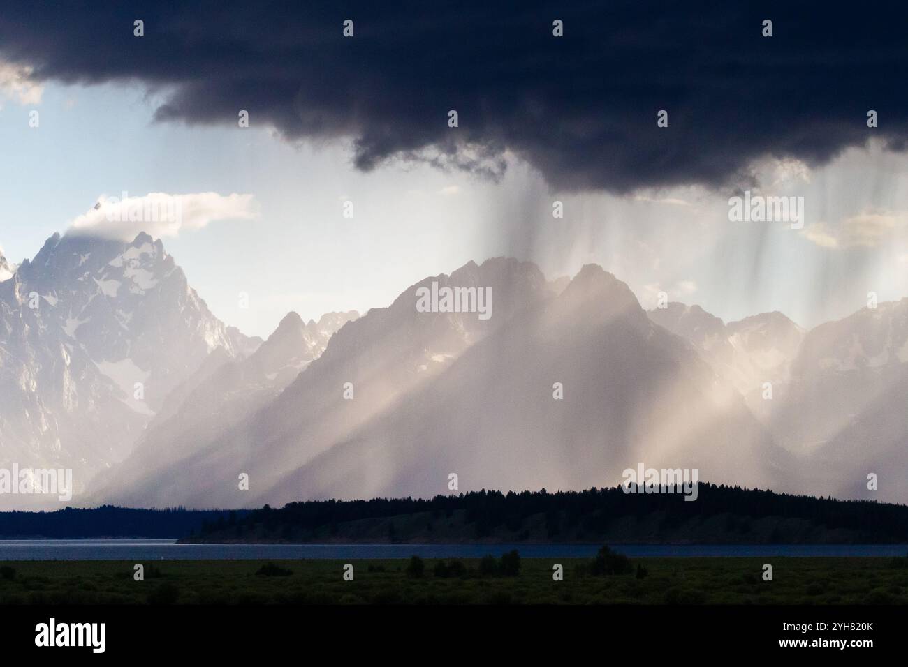 Light rays break through storm clouds hitting rain above the Teton ...