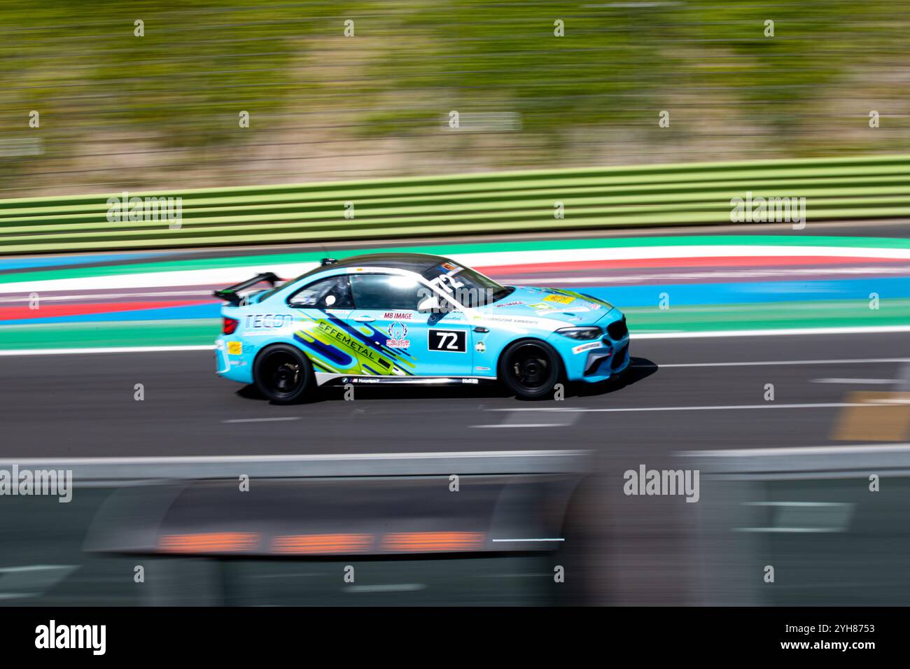 Light blue racing car speeding on a racetrack on a sunny day during a ...