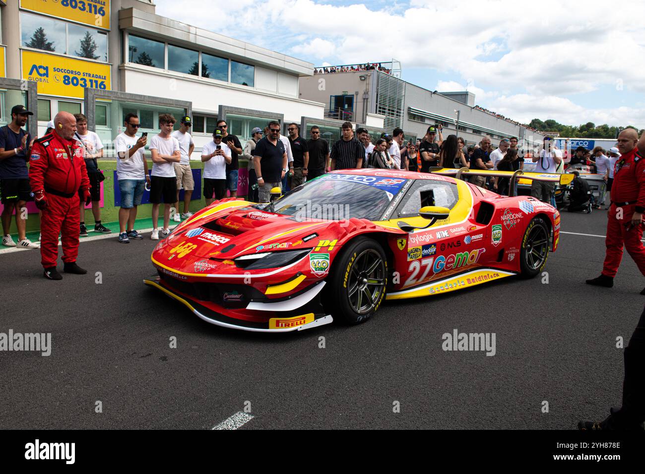 Red and yellow Ferrari GT racing car entering the starting grid ...