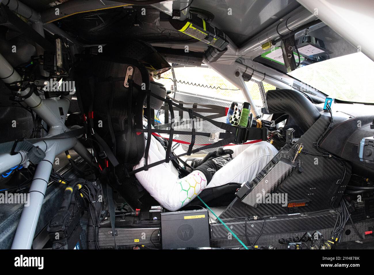 Race car driver wearing helmet and safety gear sits in car, preparing ...