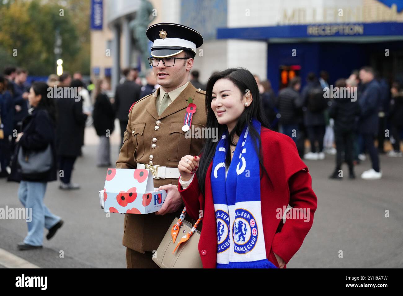 A member of the armed forces sells poppy badges to fans outside ...