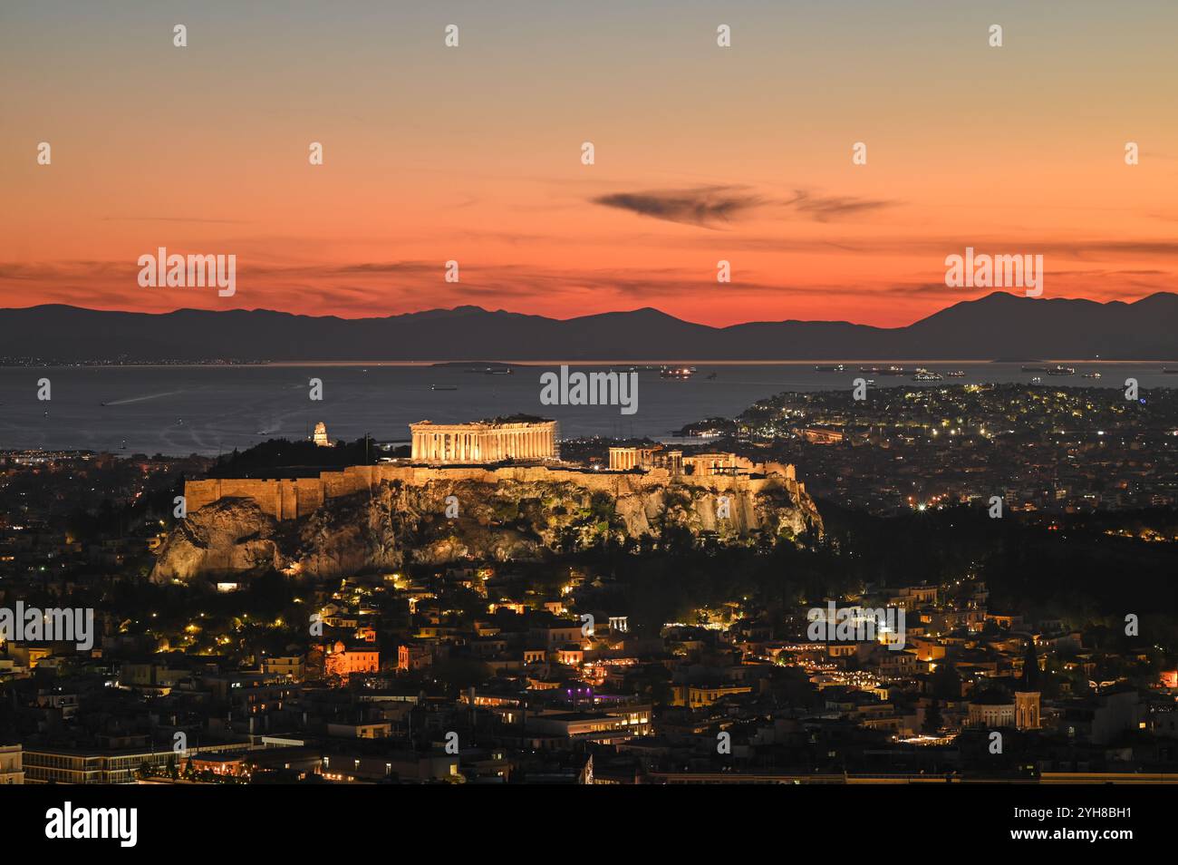 A view of Athens city and the Acropolis hill with the Parthenon Temple illuminated during sunset ...