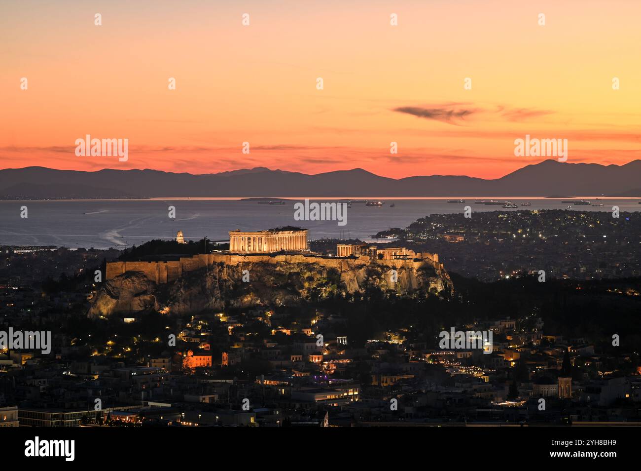 A view of Athens city and the Acropolis hill with the Parthenon Temple illuminated during sunset ...