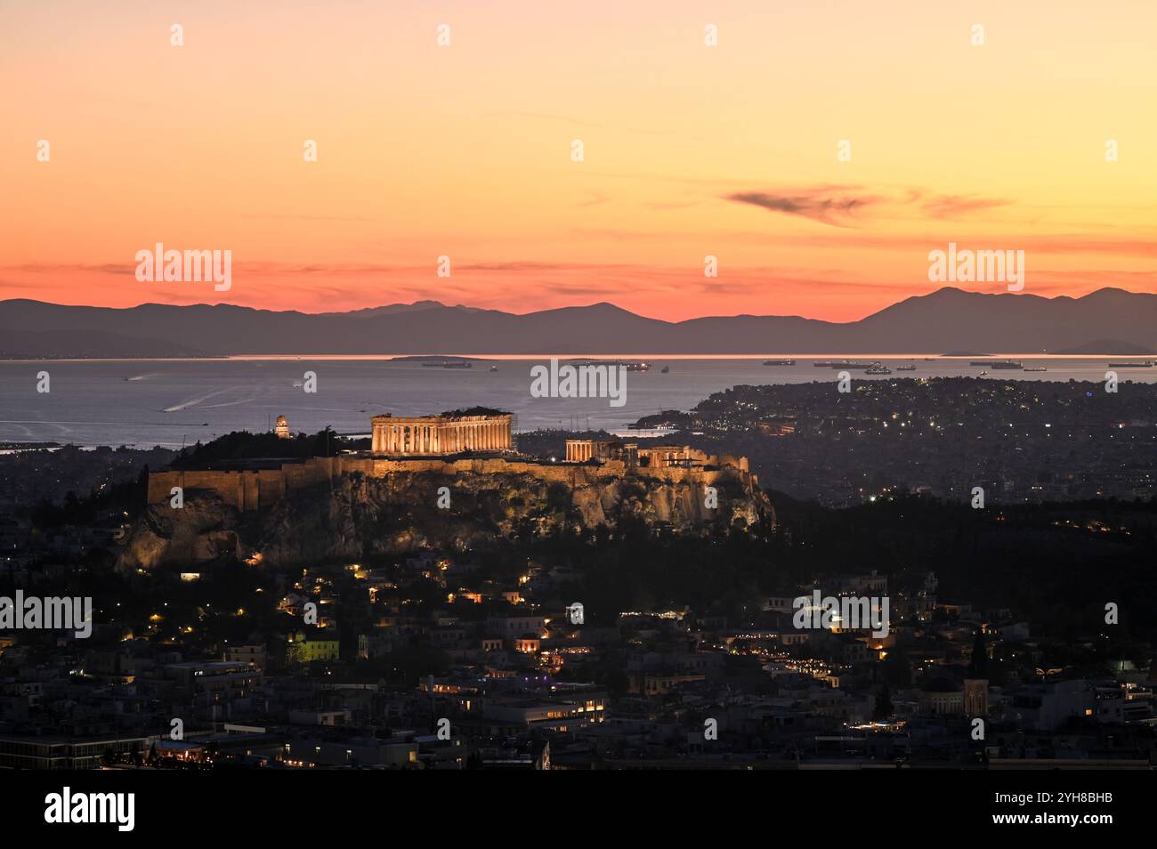 A view of Athens city and the Acropolis hill with the Parthenon Temple illuminated during sunset ...
