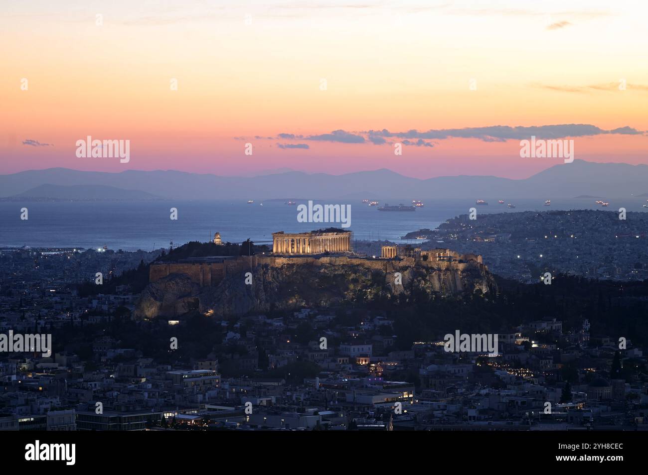 A view of Athens city and the Acropolis hill with the Parthenon Temple illuminated during sunset ...