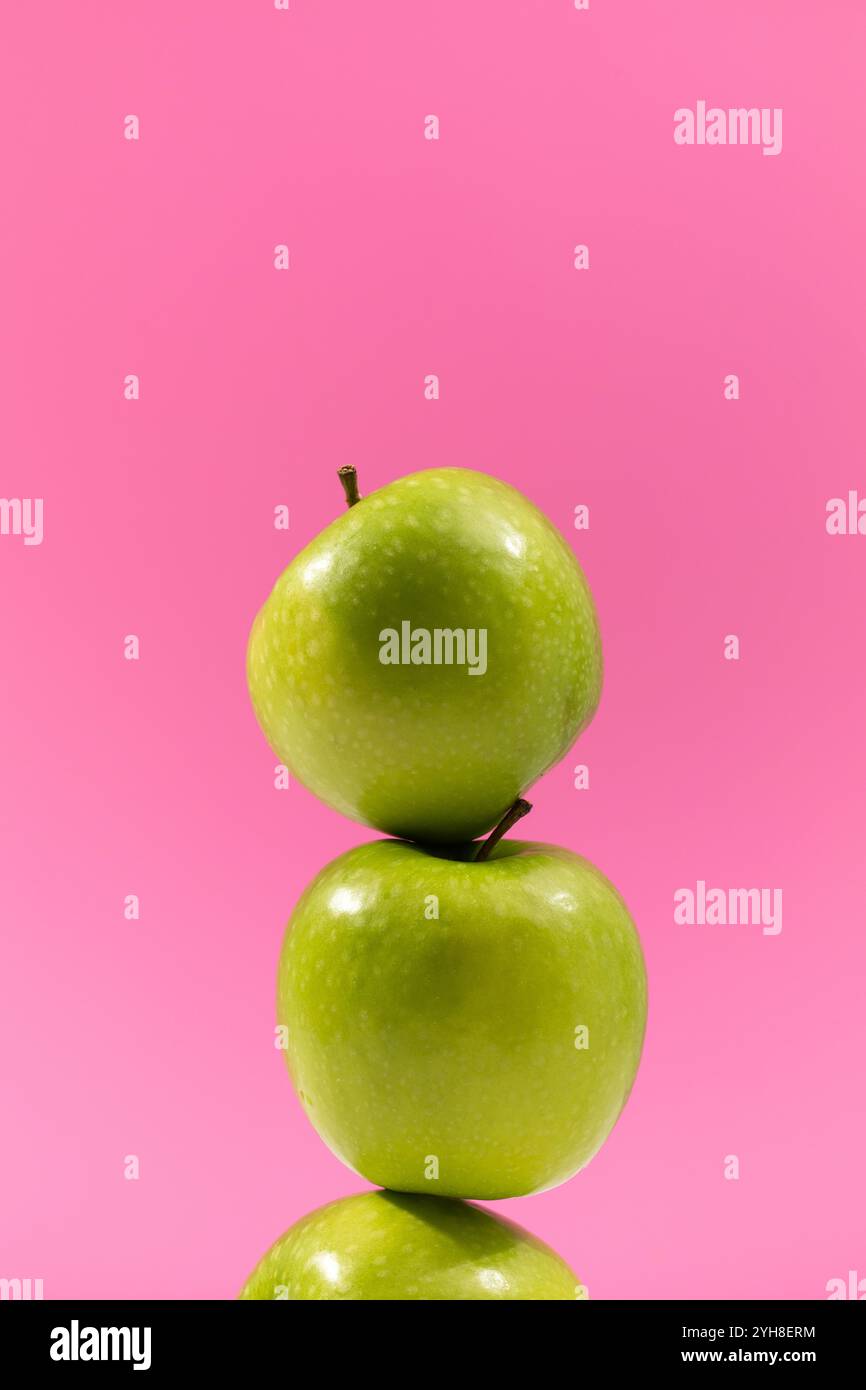 Lush green apples stack balances on vibrant pink background Stock Photo ...