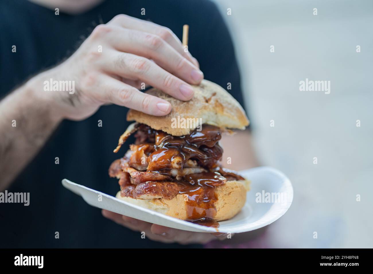 Close up of a person holding a huge sausage and bacon bap, a ...