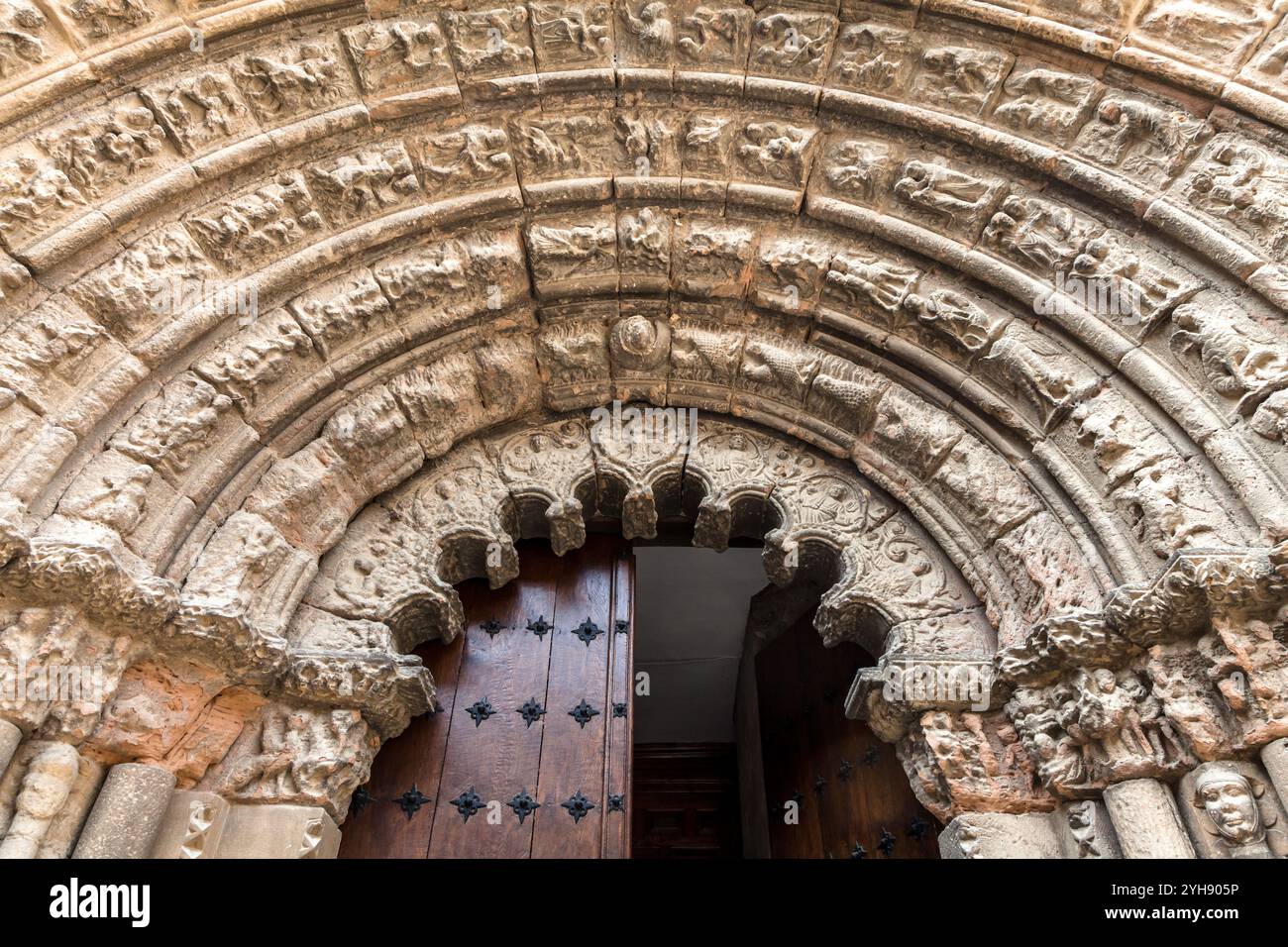 A beautifully carved stone archway frames the large wooden doors of an ...
