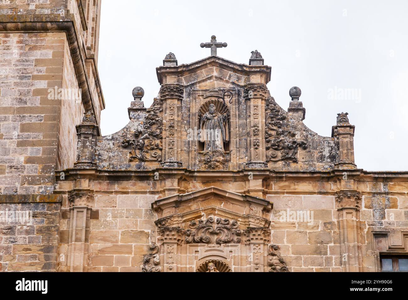 A detailed stone carving showcases a figure adorned with intricate ...