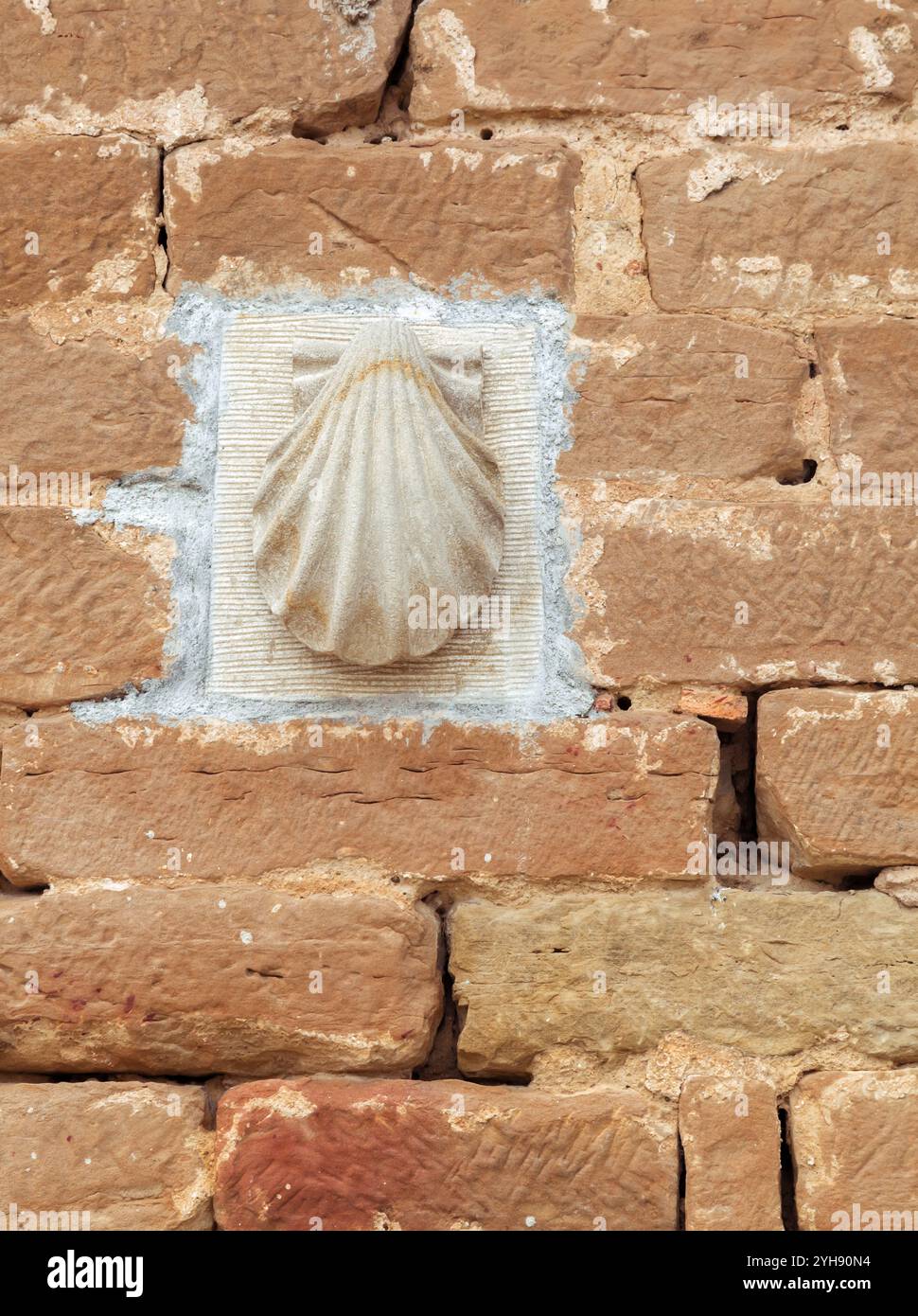 A shell symbol, representing pilgrimage, is affixed to a rustic brick ...