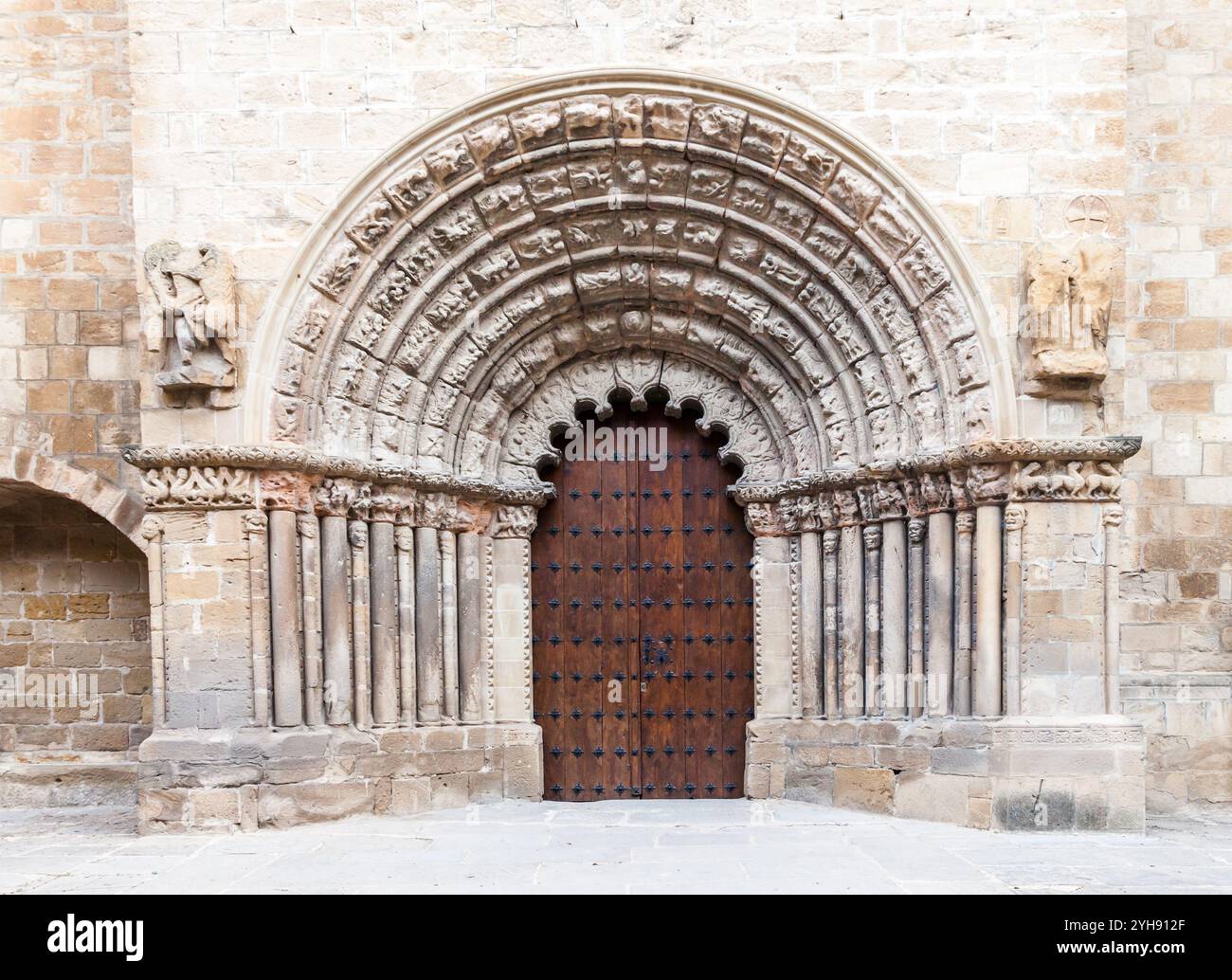 A beautifully carved stone archway frames the large wooden doors of an ...