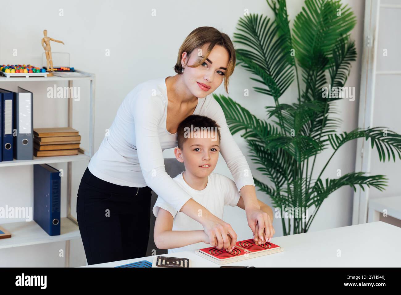 A female teacher conducts developmental training sessions with a boy ...
