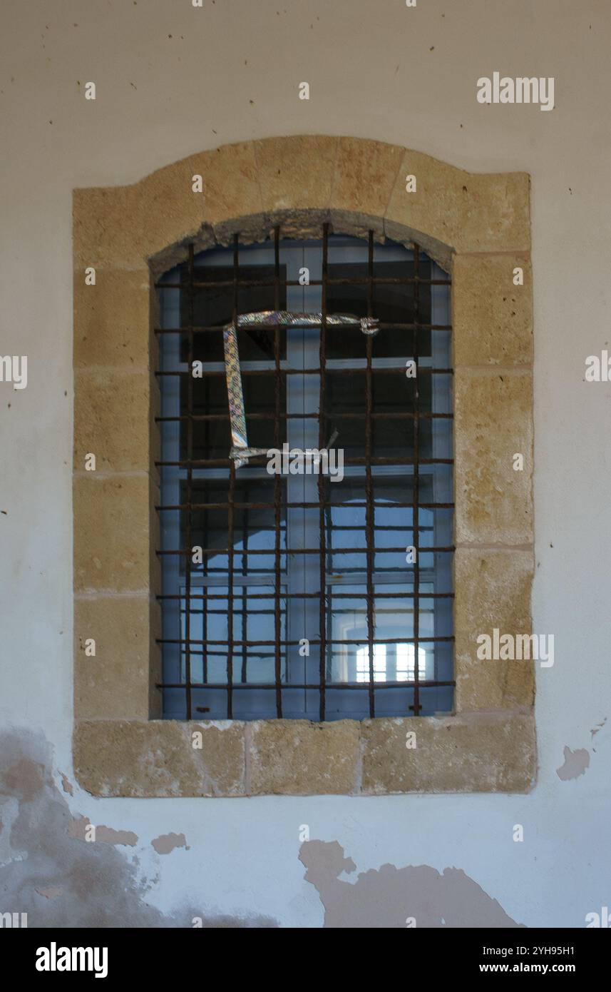 The old stone window frame features iron bars, highlighting a blend of ...