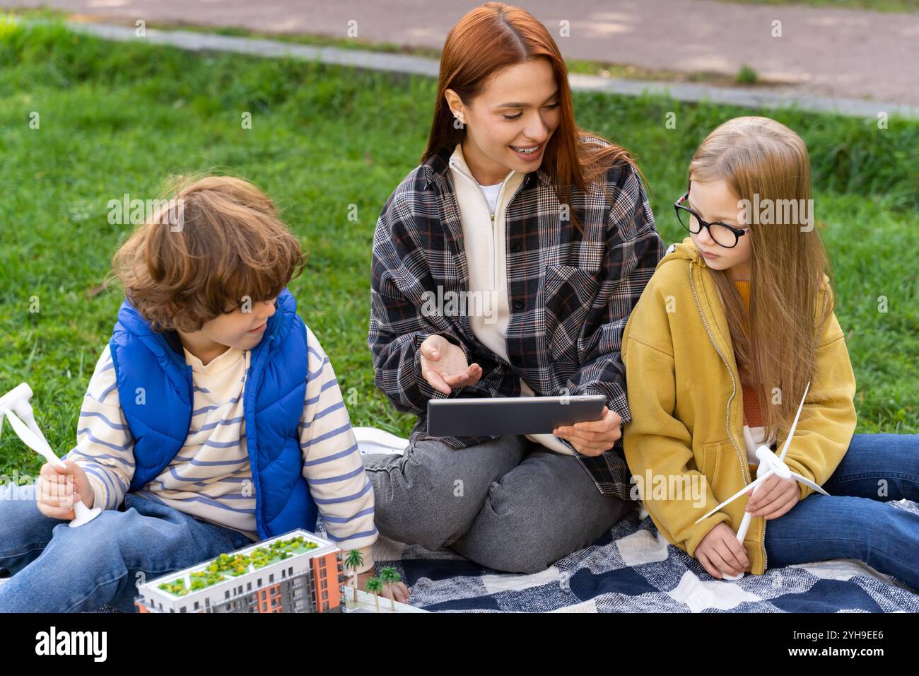 Woman volunteering at camp with children using models of wind turbines ...