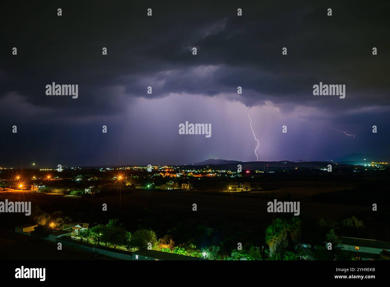 Bright flashes of lightning illuminate the dark clouds above a peaceful ...