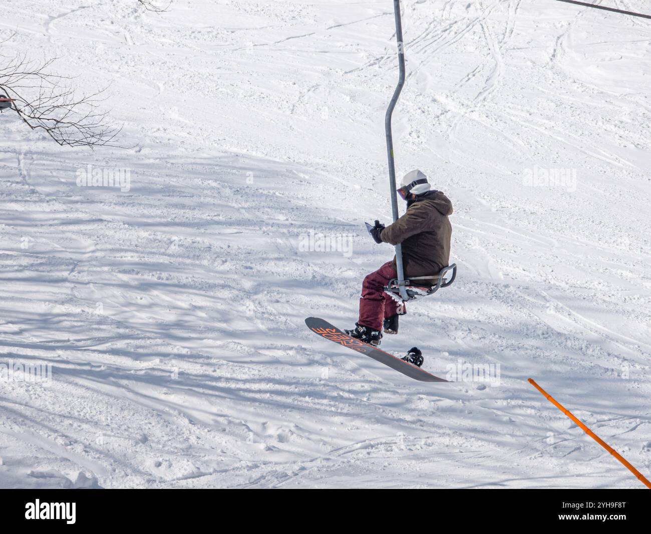 Snowboarders using a very old "Pizza Box" style single person chairlift ...