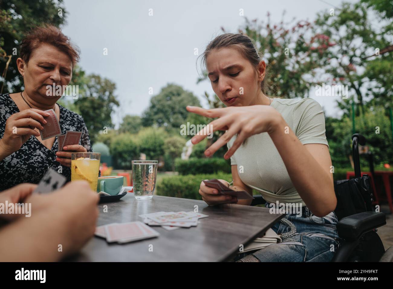 Women enjoying a lively card game at a cafe table outdoors Stock Photo ...