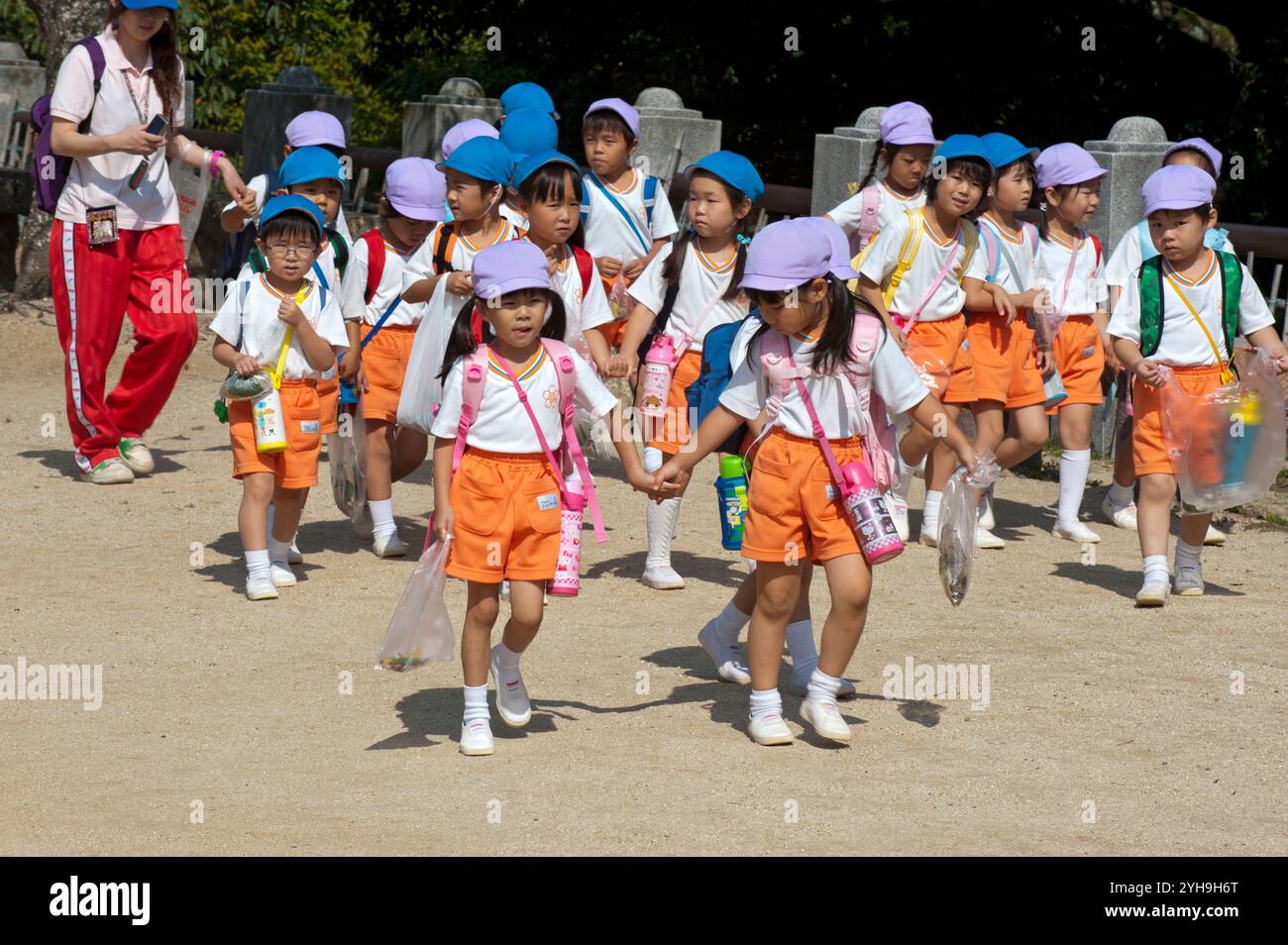 Group of kindergarten school children in matching caps and uniforms on ...