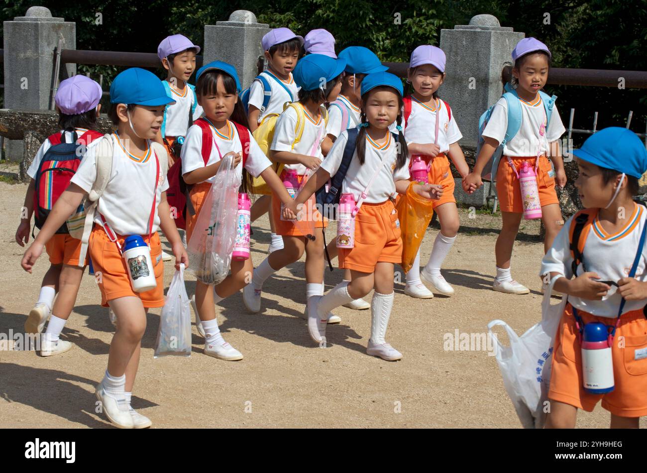 Group of kindergarten school children in matching caps and uniforms on ...