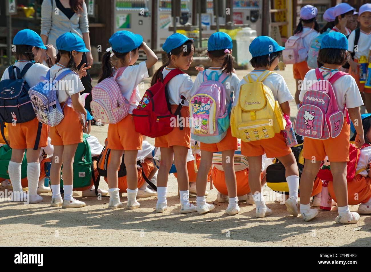 Group of kindergarten school children in matching caps and uniforms on ...