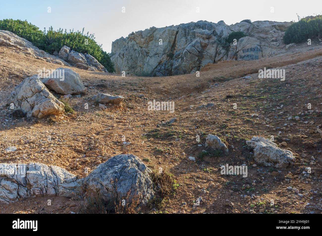 Golden sunlight illuminates a winding pathway leading through a rocky ...