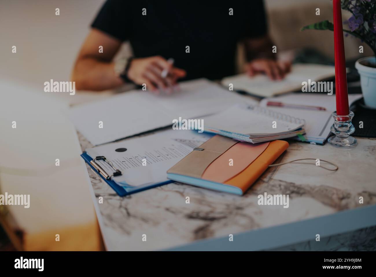 College student studying at home with notebooks and papers on desk ...