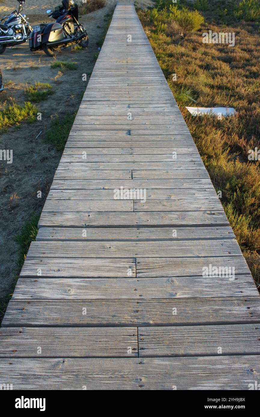 A wooden pathway stretches ahead, guiding visitors through lush grass ...