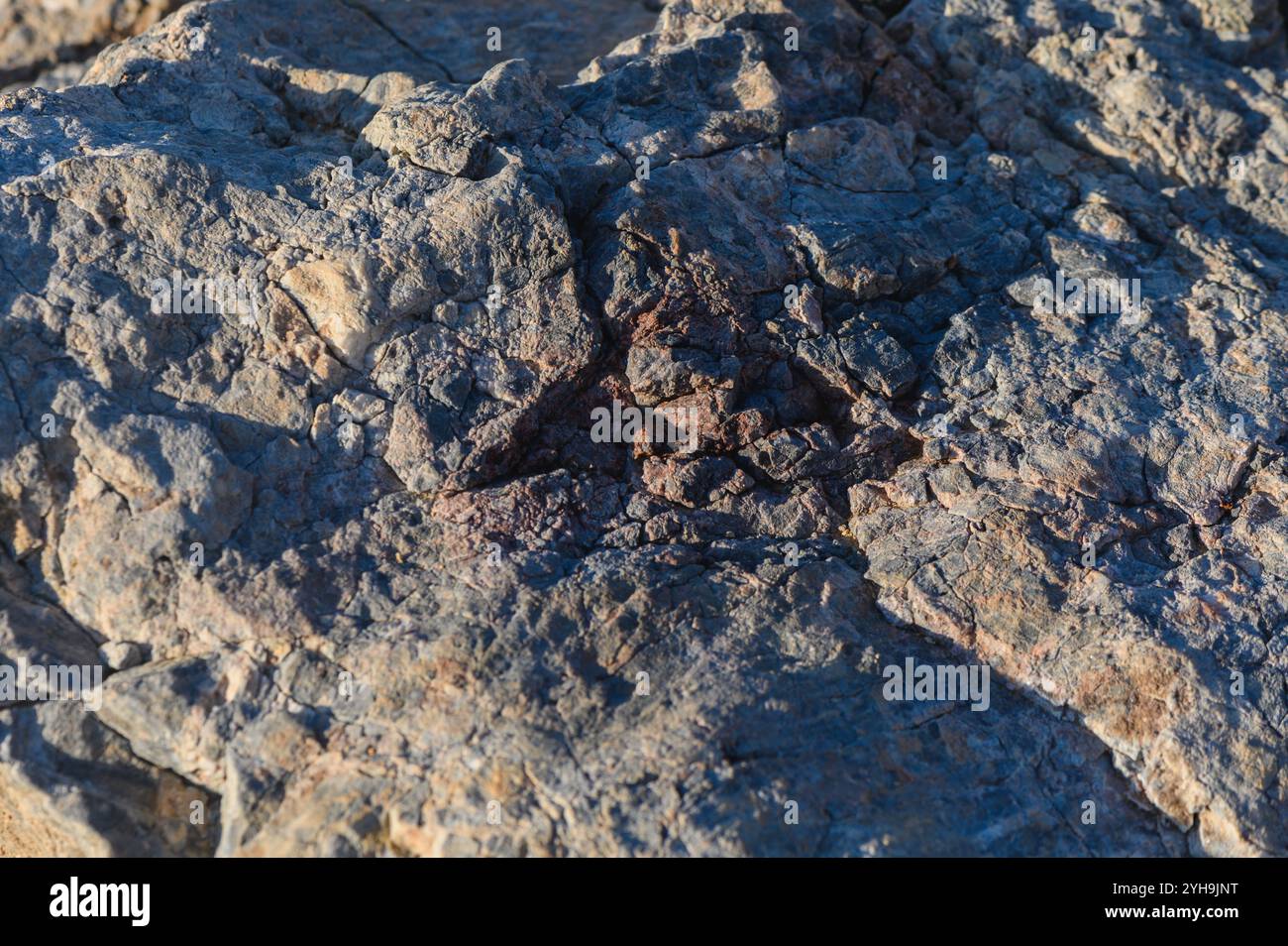 Sunlight highlights intricate textures of rugged rock formations ...