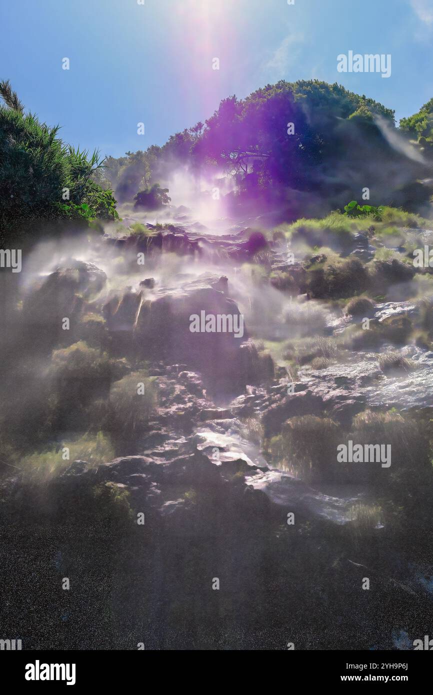 A mystical scene of mist rising from the rocky slopes of a waterfall ...