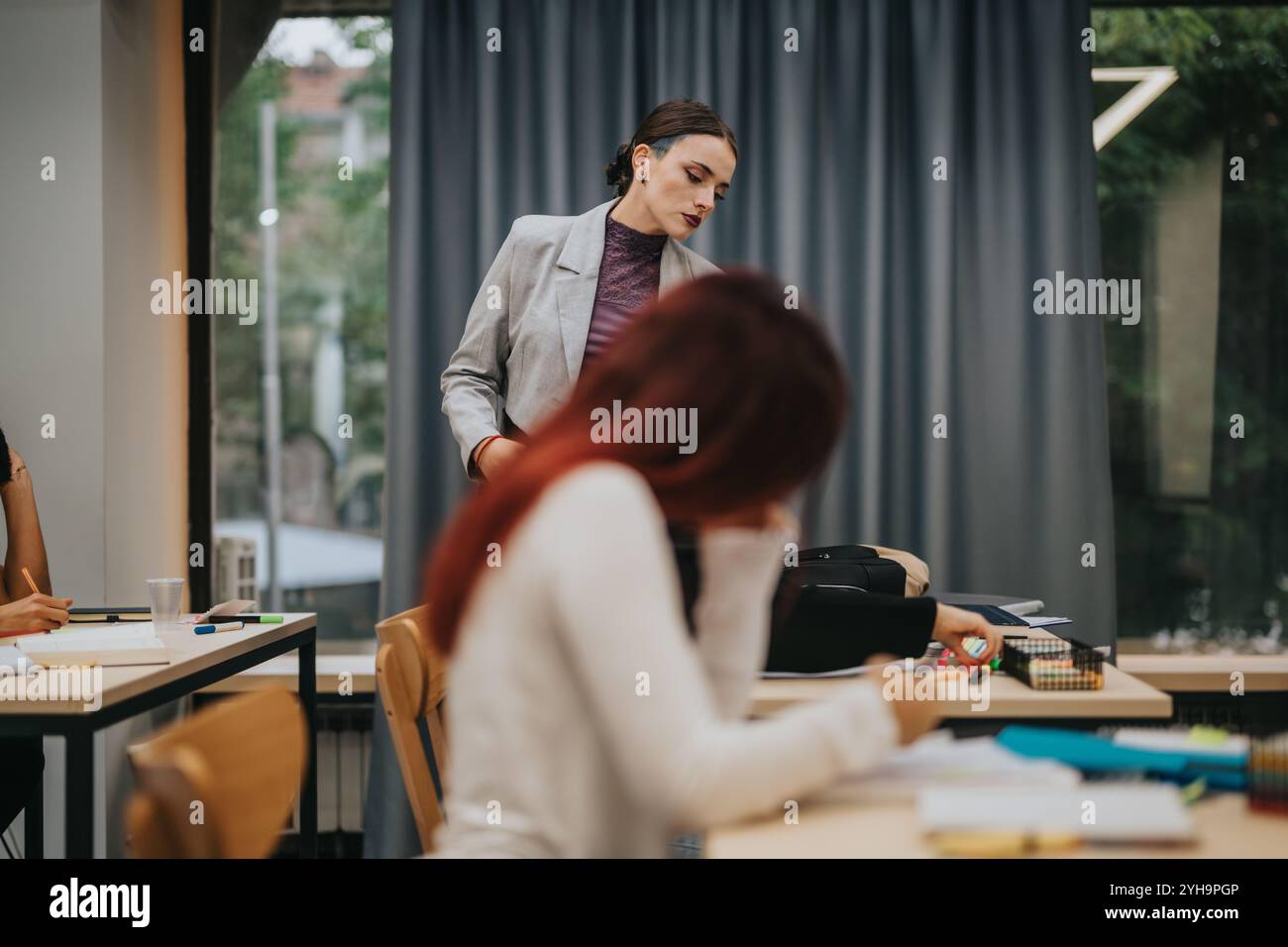 Teacher guiding students in a modern classroom setting Stock Photo - Alamy