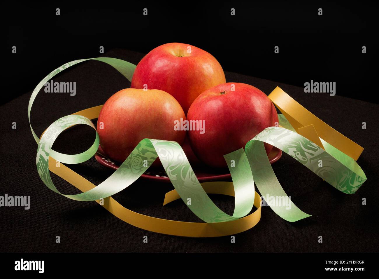 Red apples on a black background with color ribbons Stock Photo - Alamy