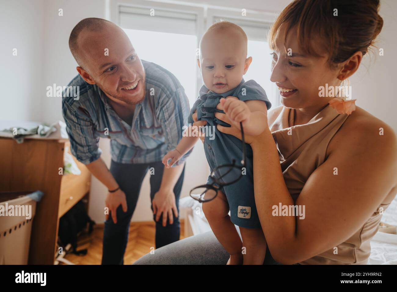 Happy parents bonding with baby in cozy home setting Stock Photo - Alamy