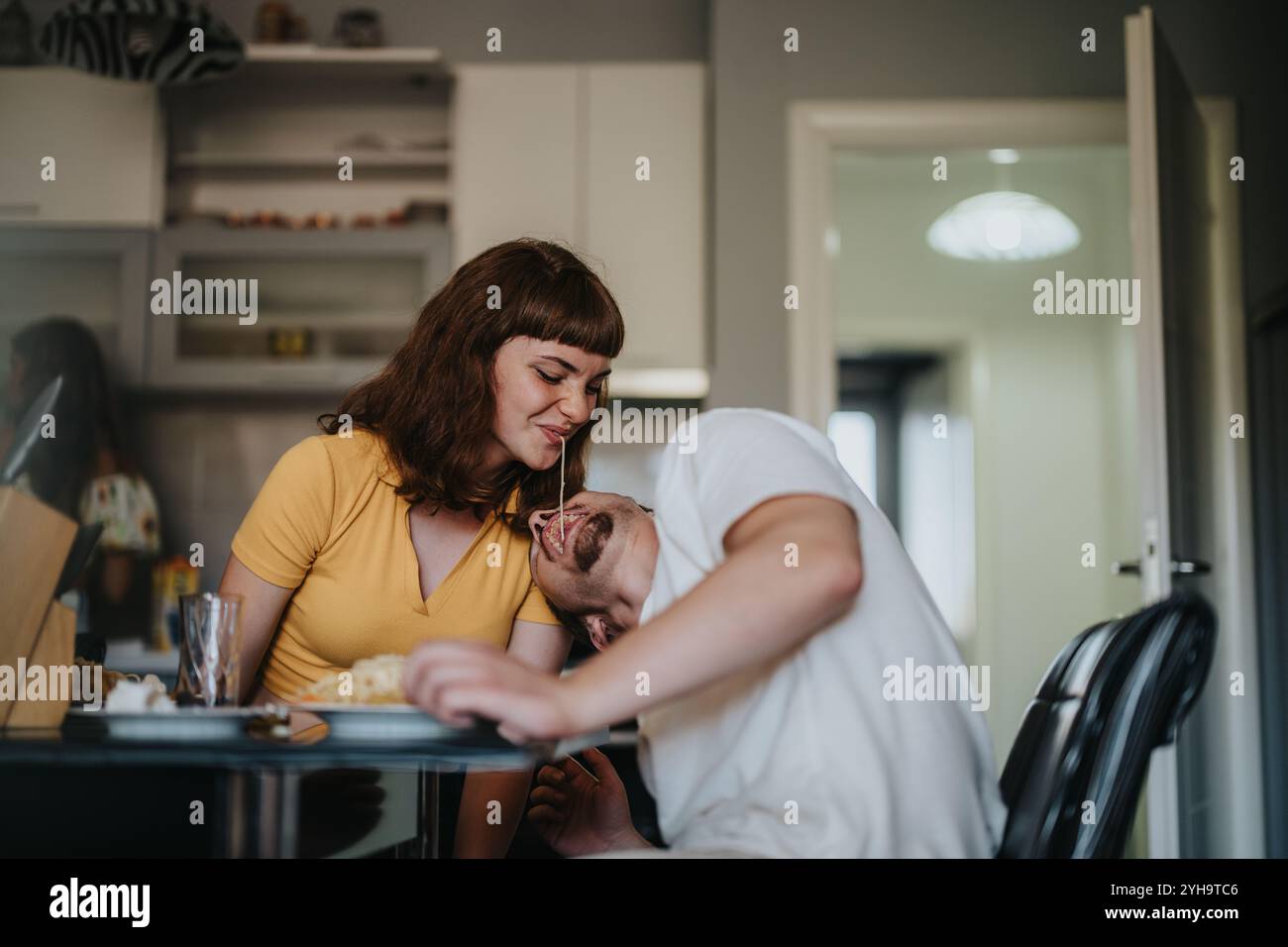 Two friends sharing spaghetti and having fun at home Stock Photo - Alamy