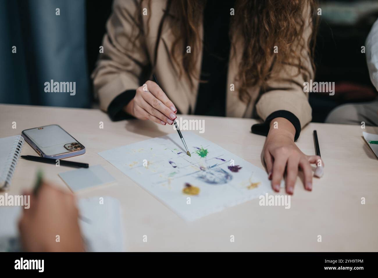 Creative student painting with watercolors in school classroom setting ...