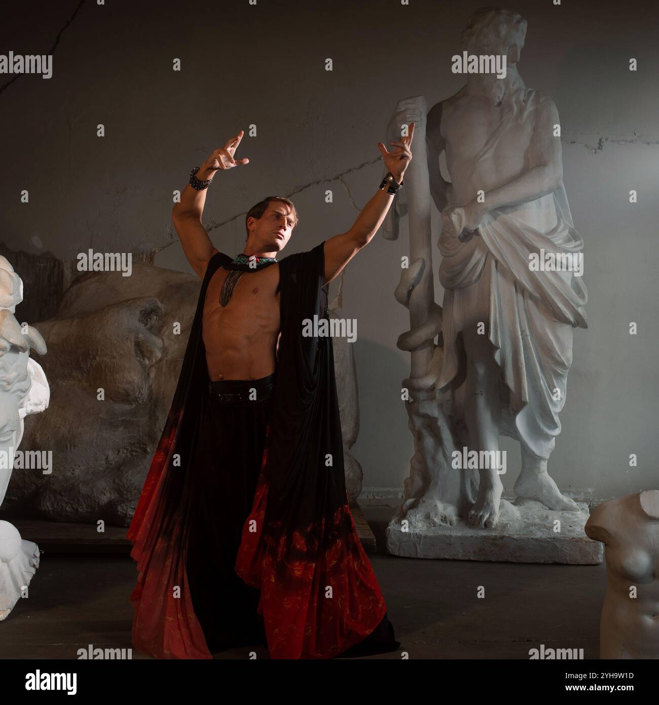 Muscular charismatic bodybuilder model in a silk cape makes an ...