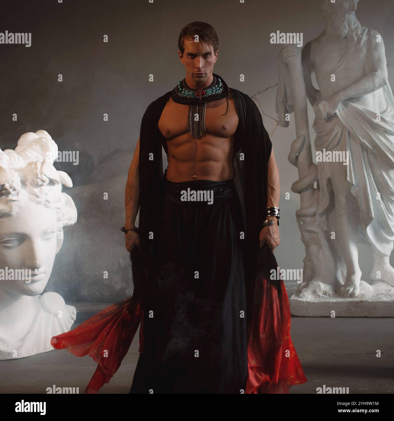 Muscular charismatic bodybuilder model in a silk cape makes an ...