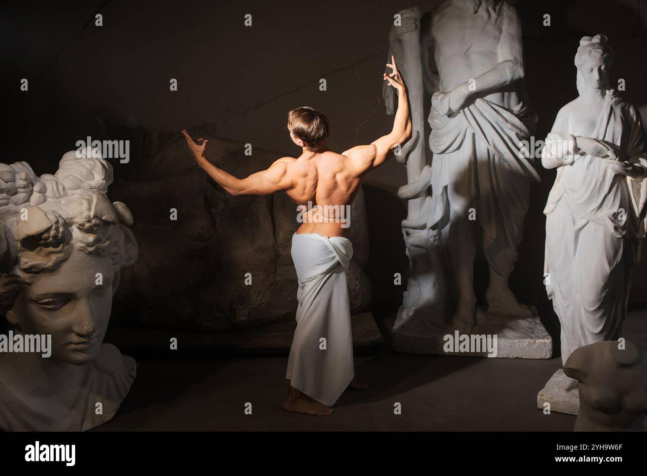 A sculptor's workshop, a muscular man in a tunic among antique statues ...