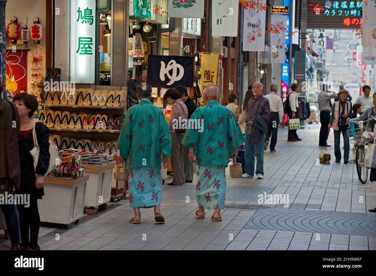 Visitors wearing traditional yukata robes walking along a shopping ...