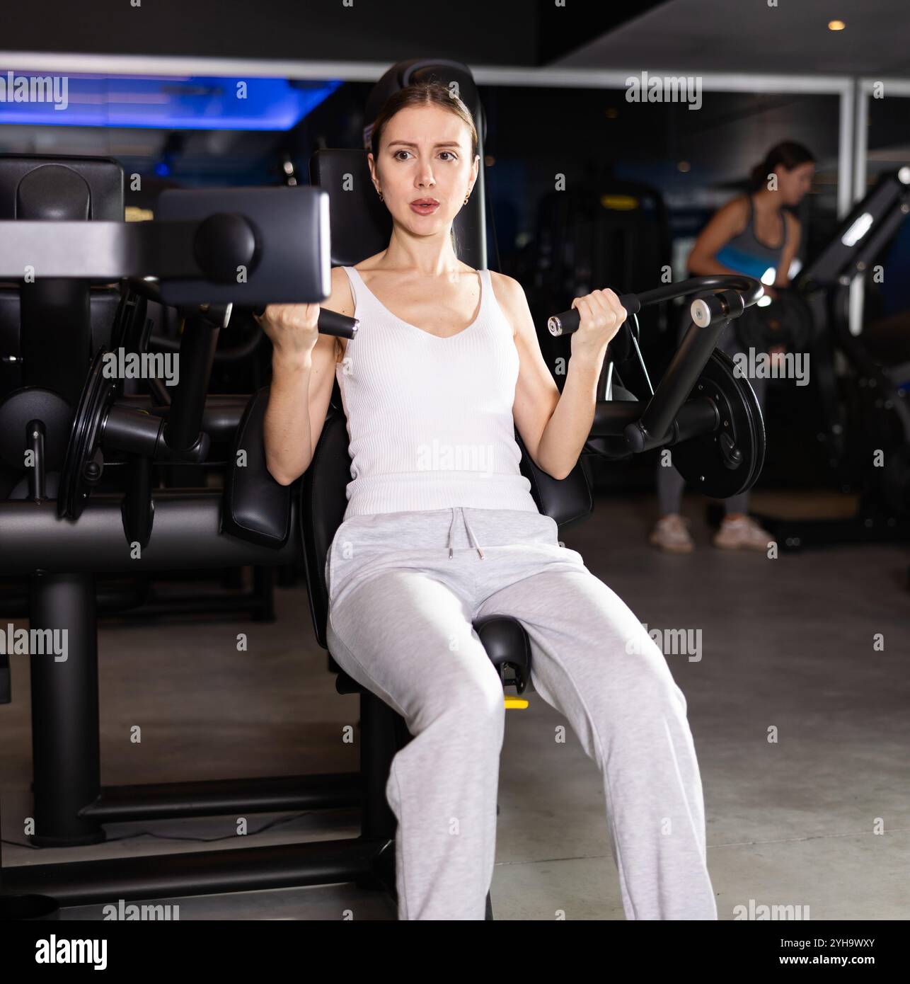 Slender athletic girl work out muscles of arms and shoulders on ...